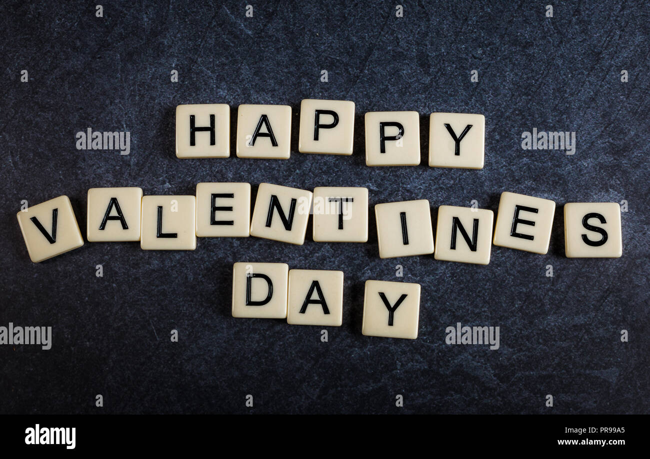 Scrabble letter tiles on black slate background spelling happy ...