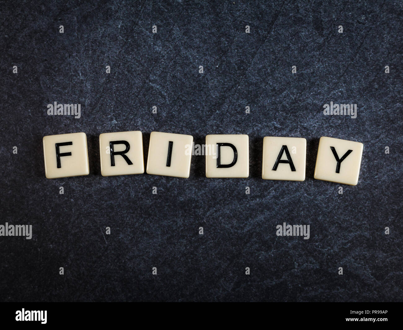 Scrabble letter tiles on black slate background spelling Friday Stock ...
