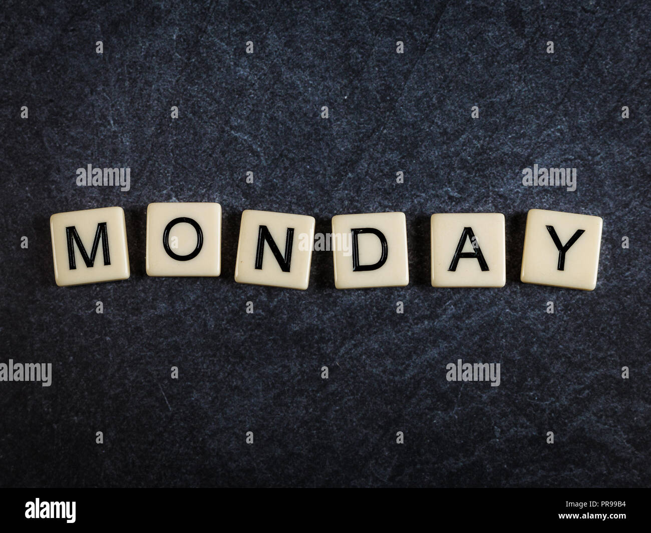 Scrabble letter tiles on black slate background spelling Monday Stock ...