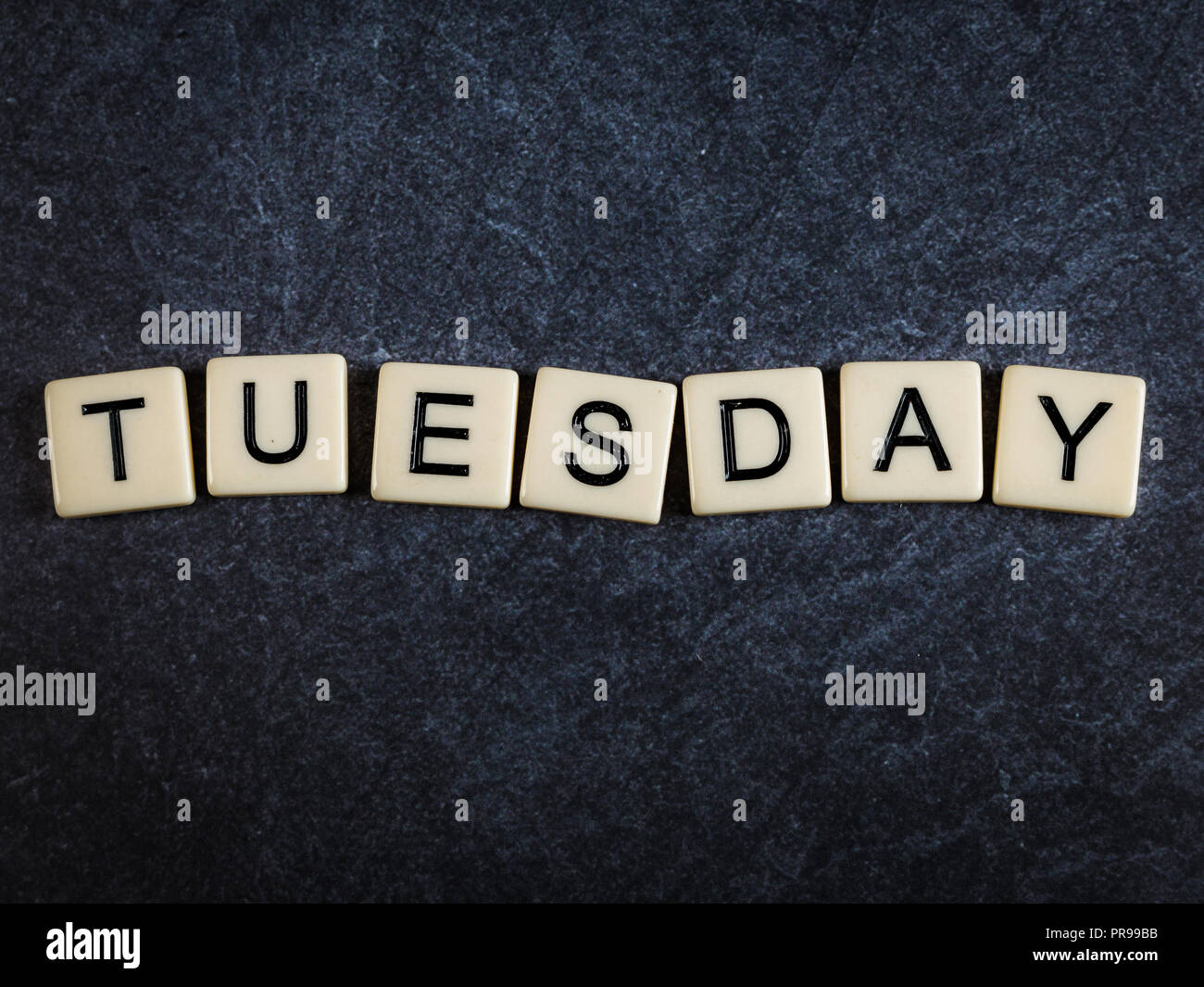 Scrabble letter tiles on black slate background spelling Tuesday Stock ...