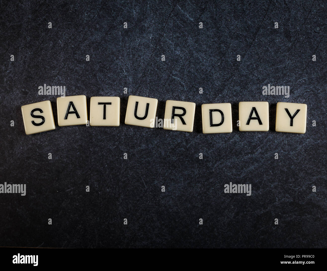 Scrabble letter tiles on black slate background spelling Saturday Stock ...