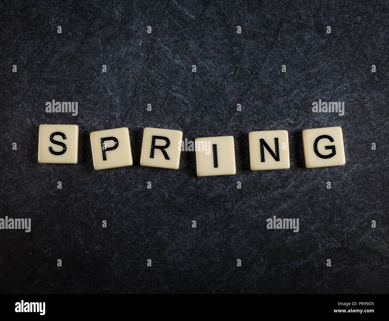 Scrabble letter tiles on black slate background spelling Spring Stock ...