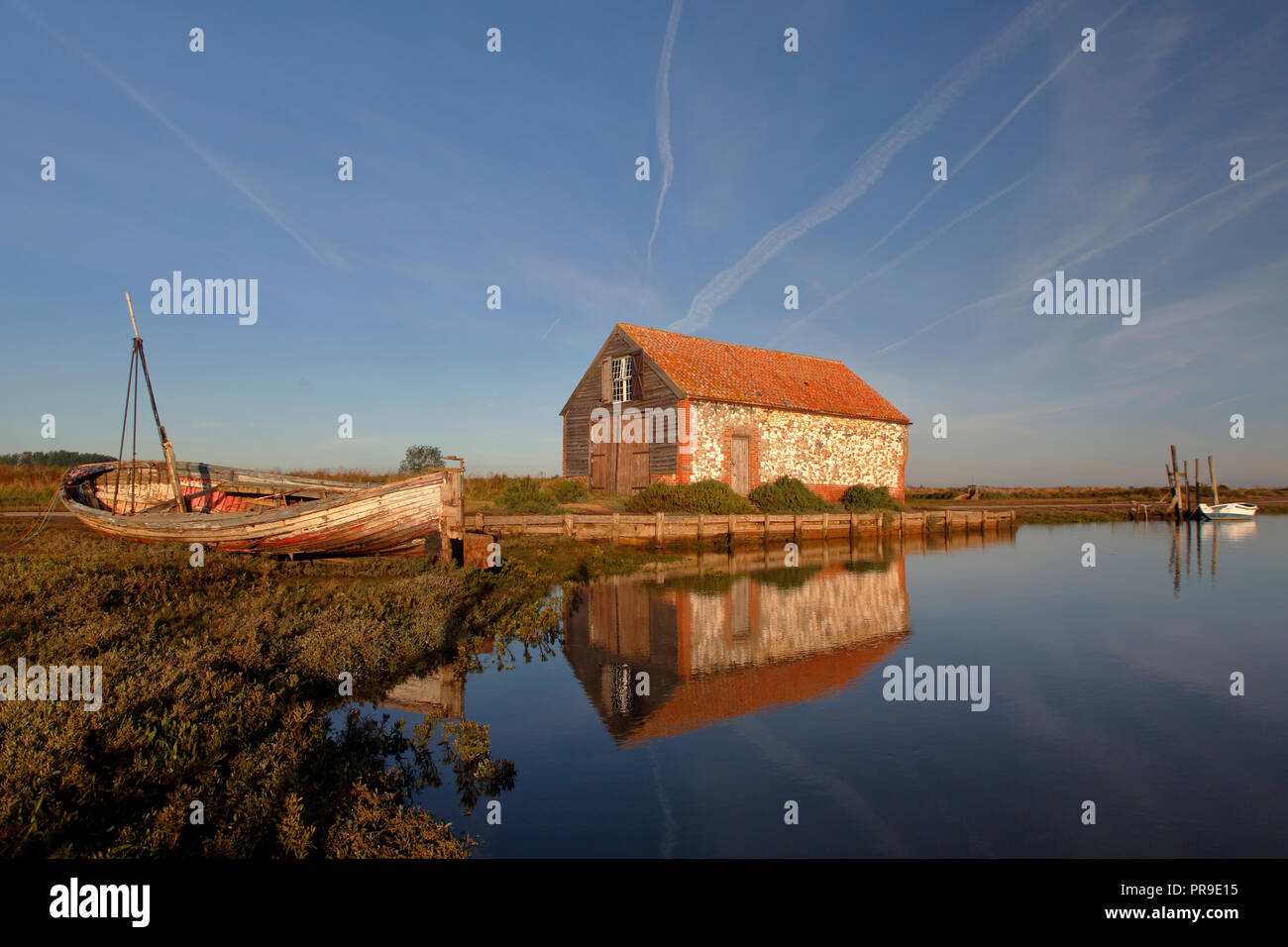 Thornham Staithe Coal Barn and harbour with derelict boat and blue sky ...