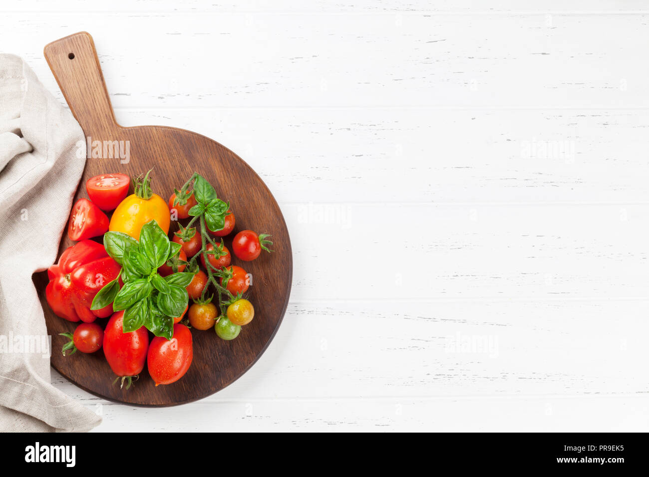 Fresh garden tomatoes and basil on cooking table. Top view with space ...