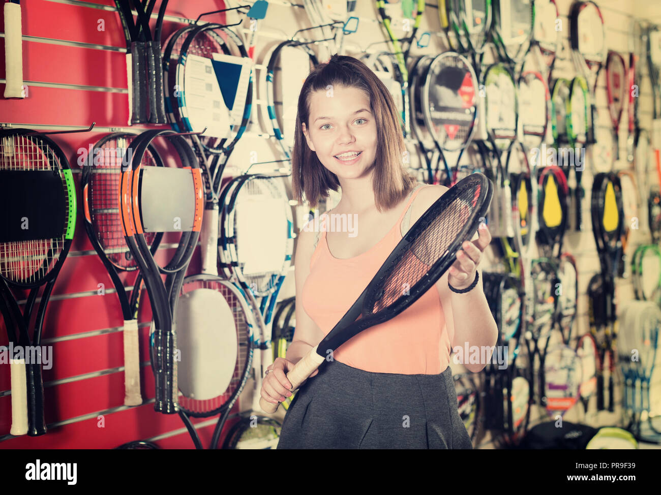 Young girl standing in sporting goods store with racket Stock Photo - Alamy