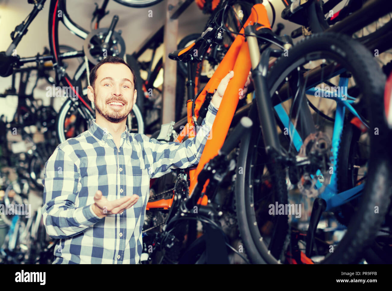 positive man in bicycle shop chooses for himself sports bike from a ...