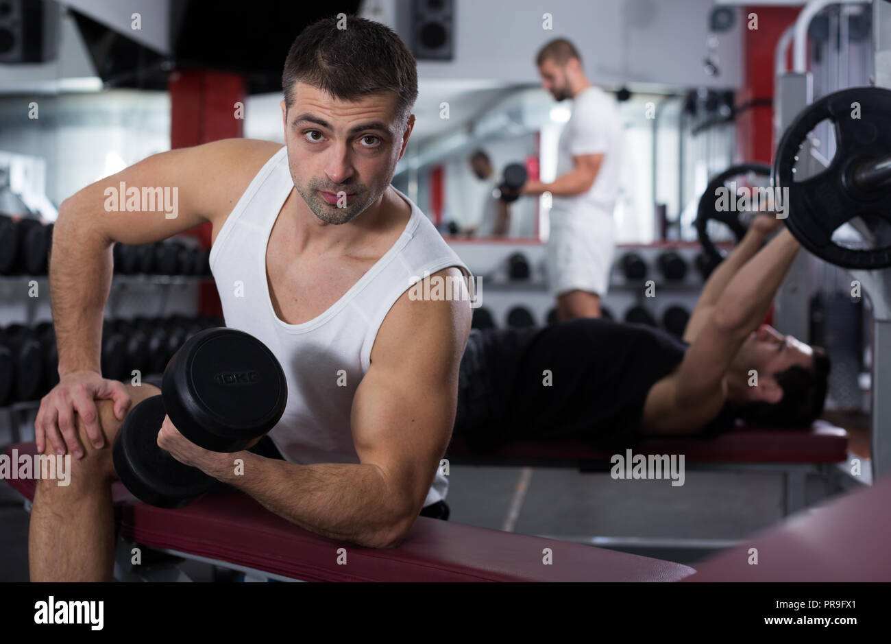 Concentrated sporty guy during workout in gym with dumbbells Stock ...