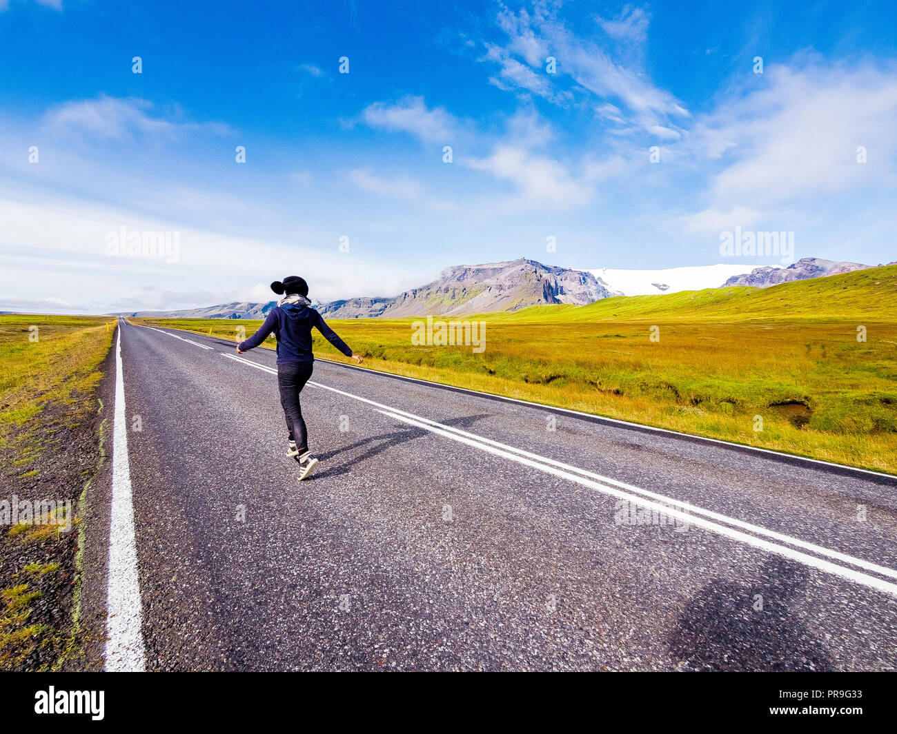 female traveler running into the horizon on the Ring Road in Iceland ...