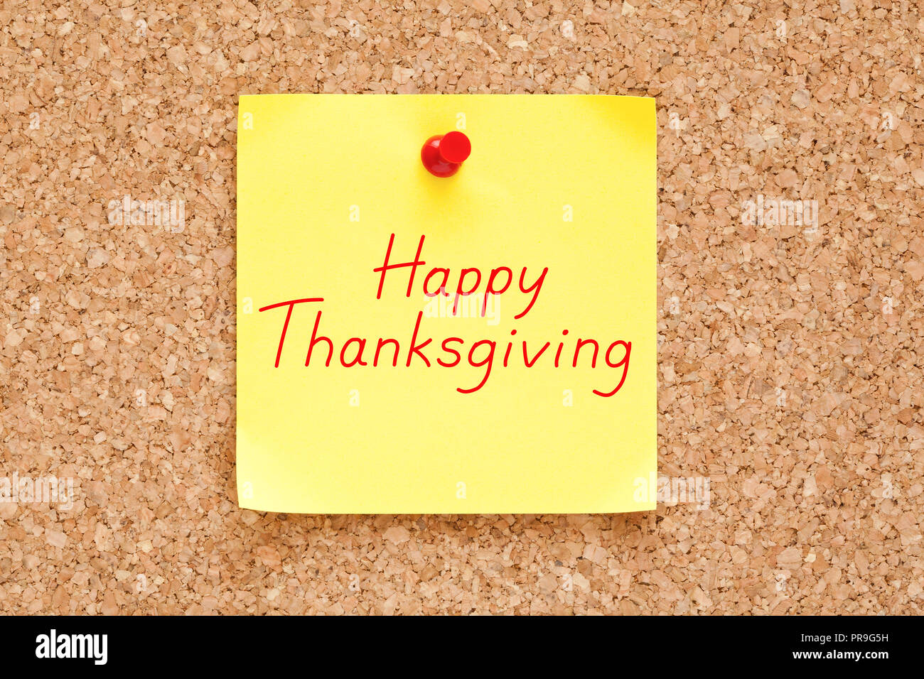 Happy Thanksgiving handwritten on yellow sticky note pinned on cork ...