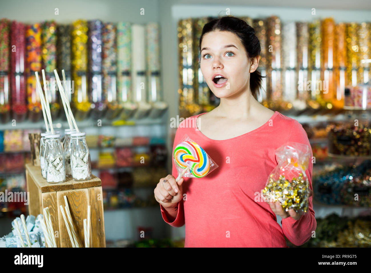 Happy brunette girl buying candies at shop Stock Photo - Alamy