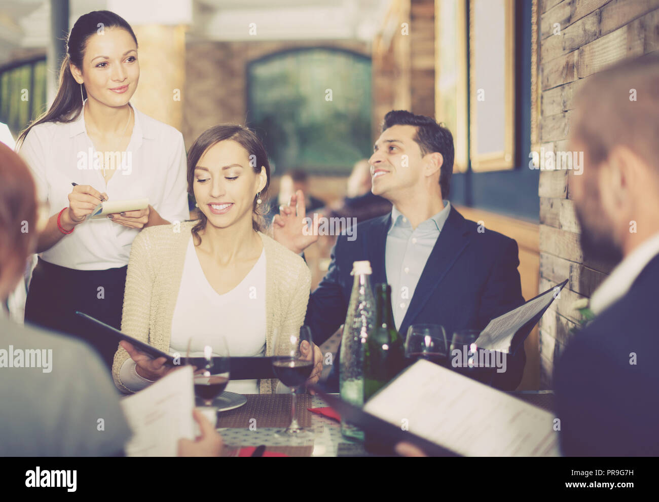 Employee waitress girl taking order from positive guests at restaurant ...
