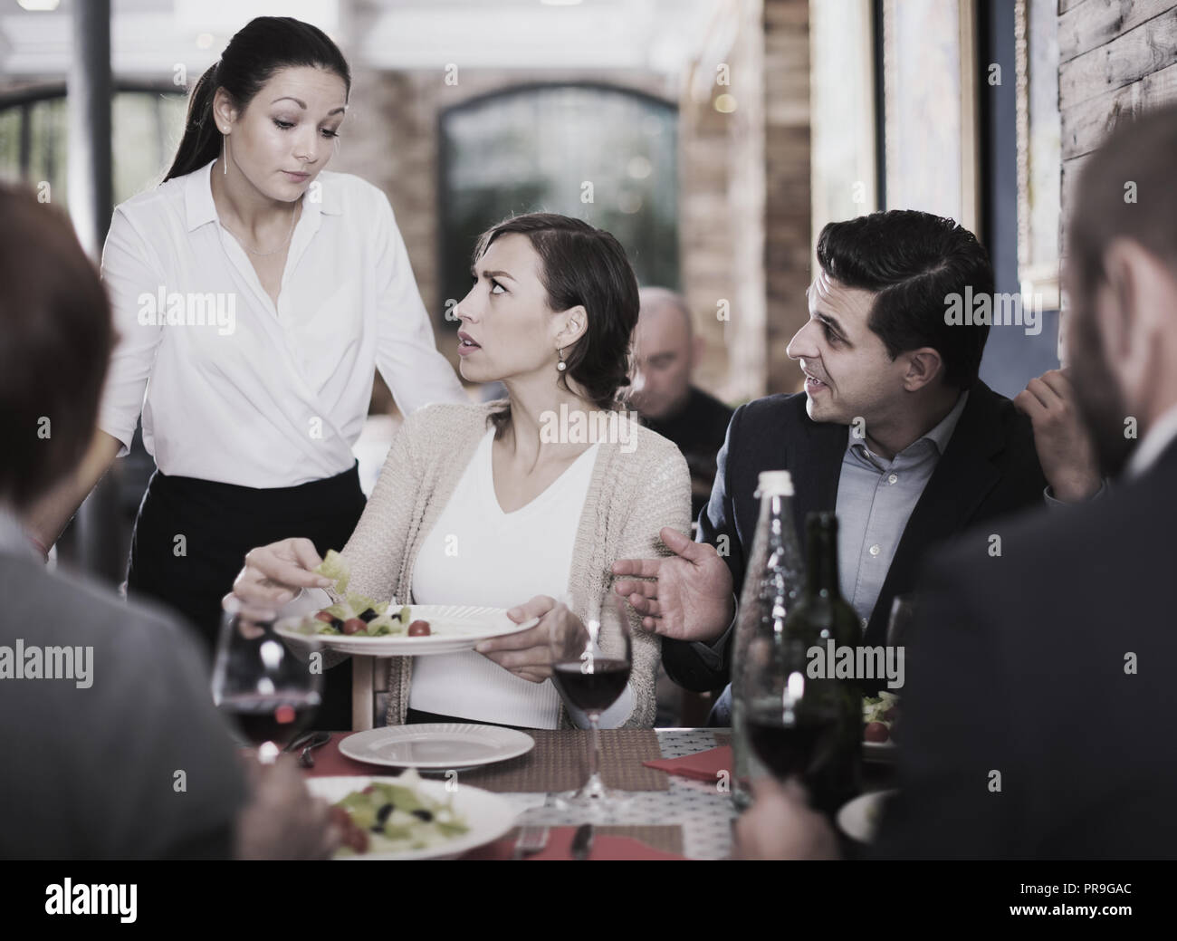 Angry female and male guests conflict with apologetic waitress about ...