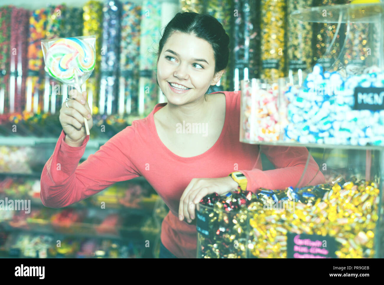 Happy brunette girl buying candies at shop Stock Photo - Alamy