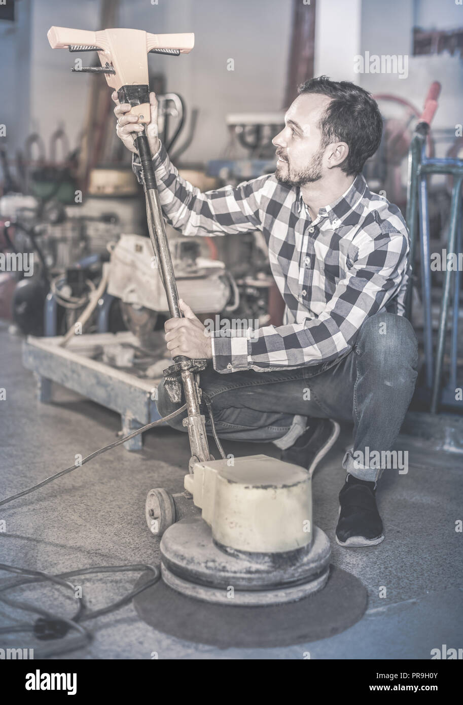 Smiling working man practicing his skills with disk sander at a ...