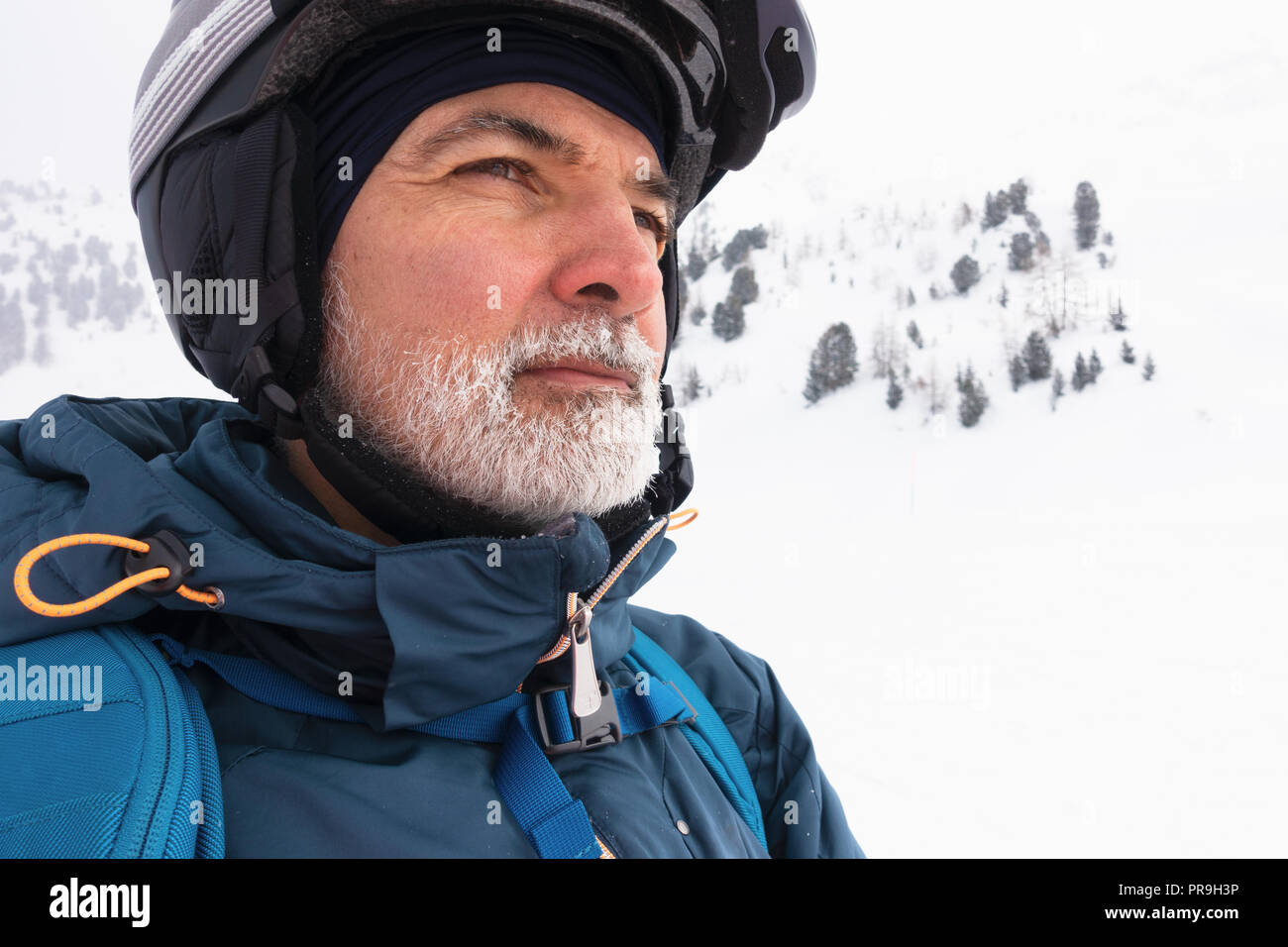 Old man with white frozen beard on snowy mountain with ski googles and ...