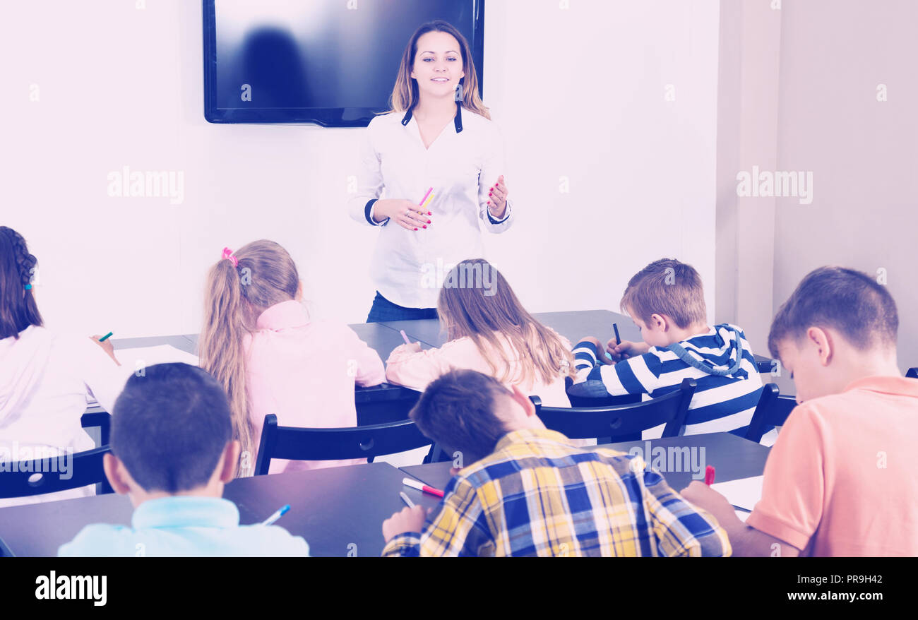 Positive young boys and girls with teacher in classroom Stock Photo - Alamy