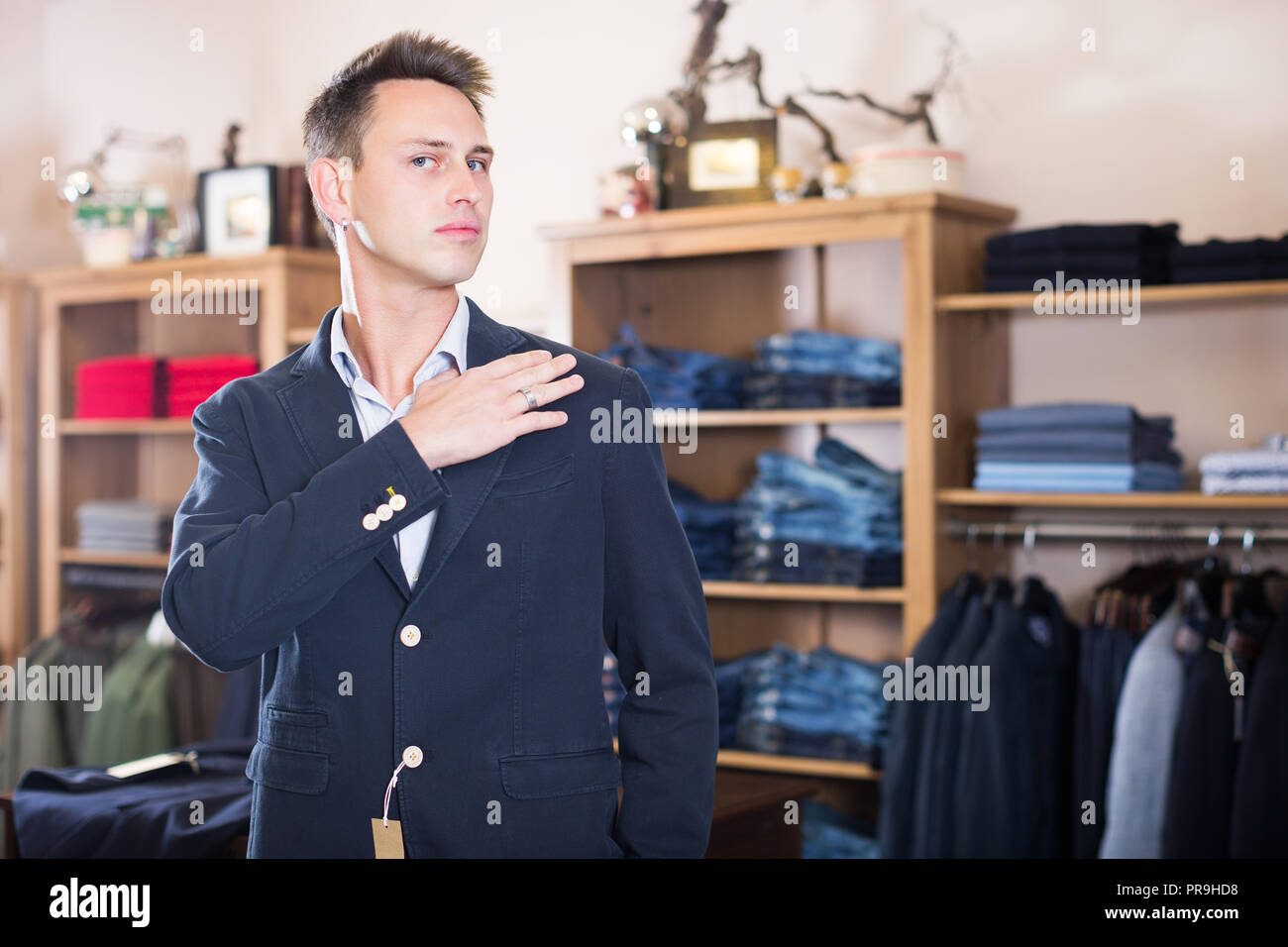 Glad young male customer examining suits in male cloths store Stock ...