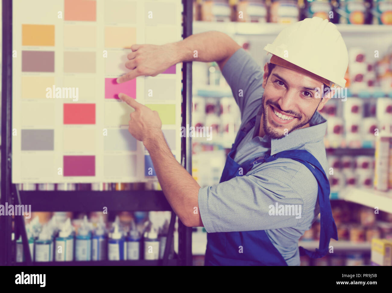 Smiling workman showing stand with samples in paint store Stock Photo ...