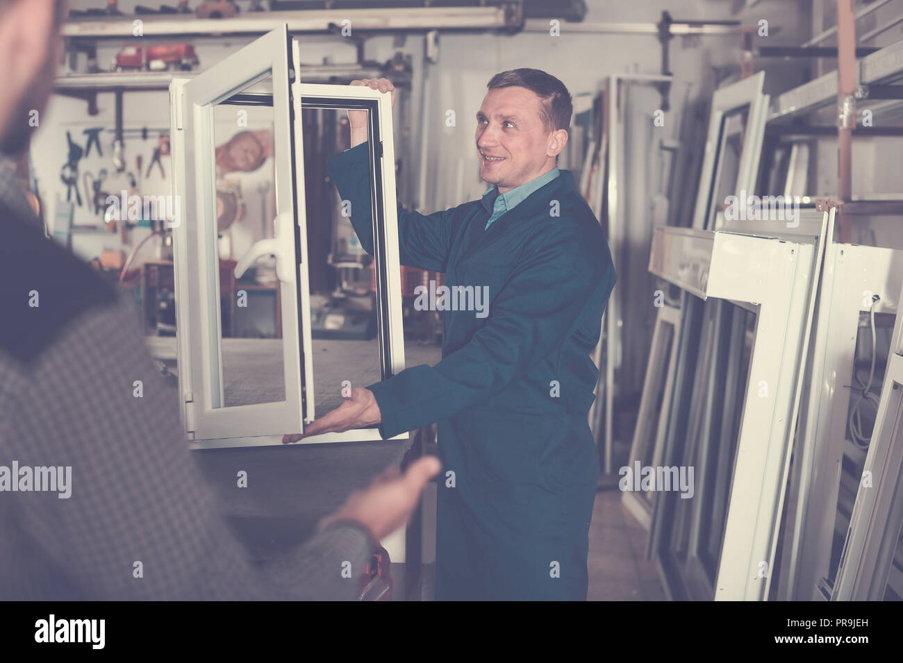 Adult labour demonstrating finished PVC profiles and windows at factory ...