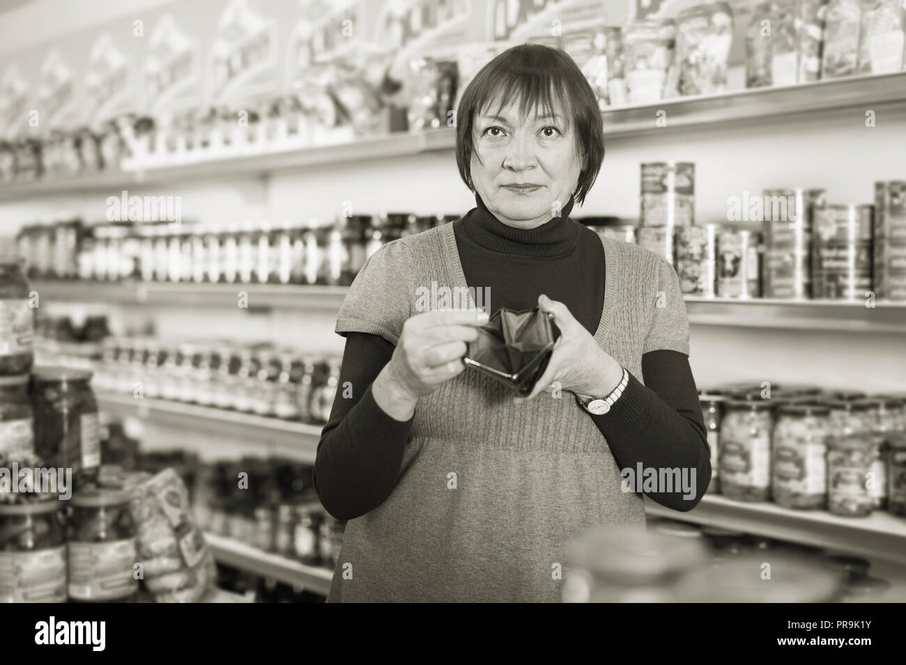 Sad woman buyer with empty purse and canned at the supermarket Stock ...