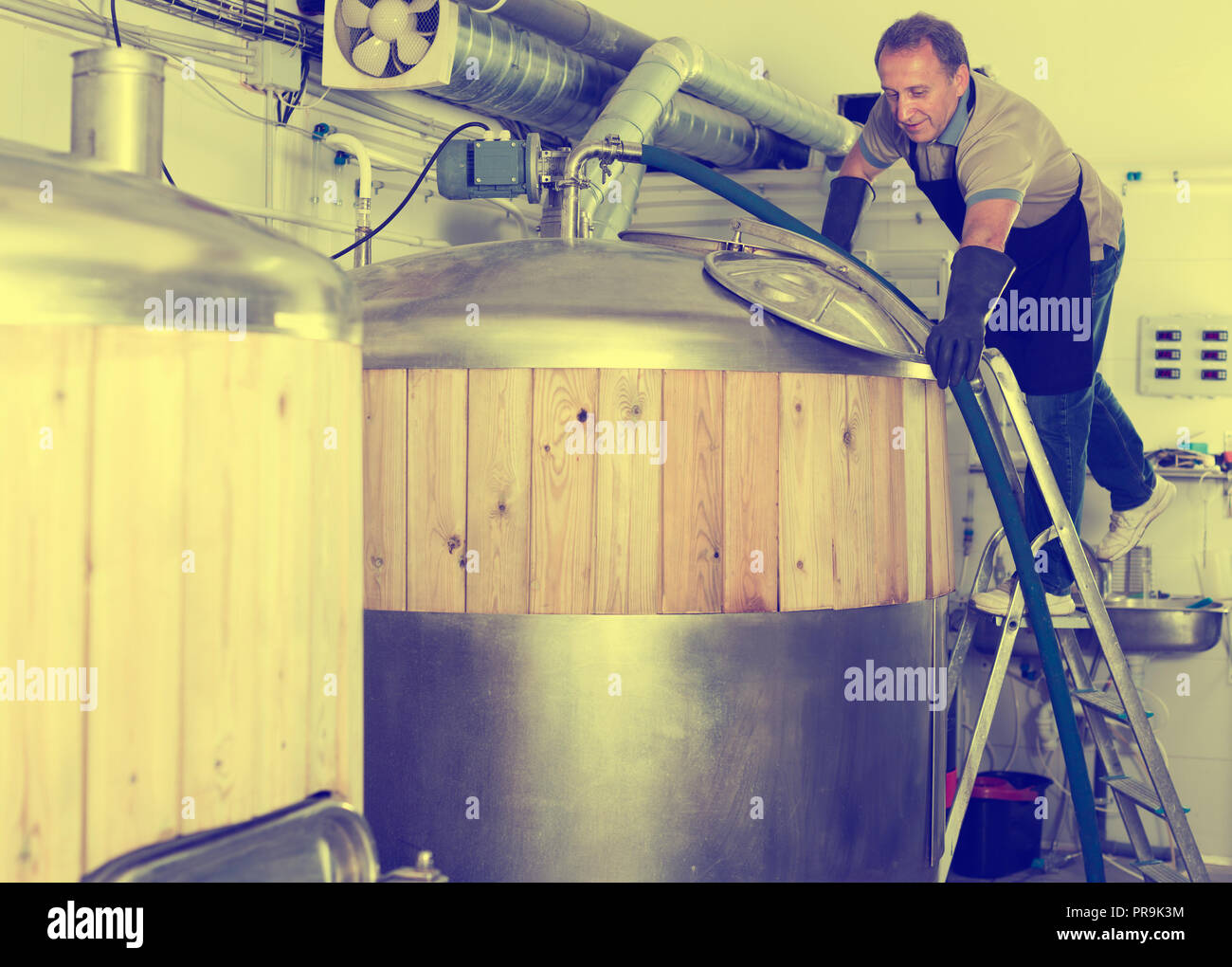 Portrait of brewer who is making beer on his workplace in the brew ...