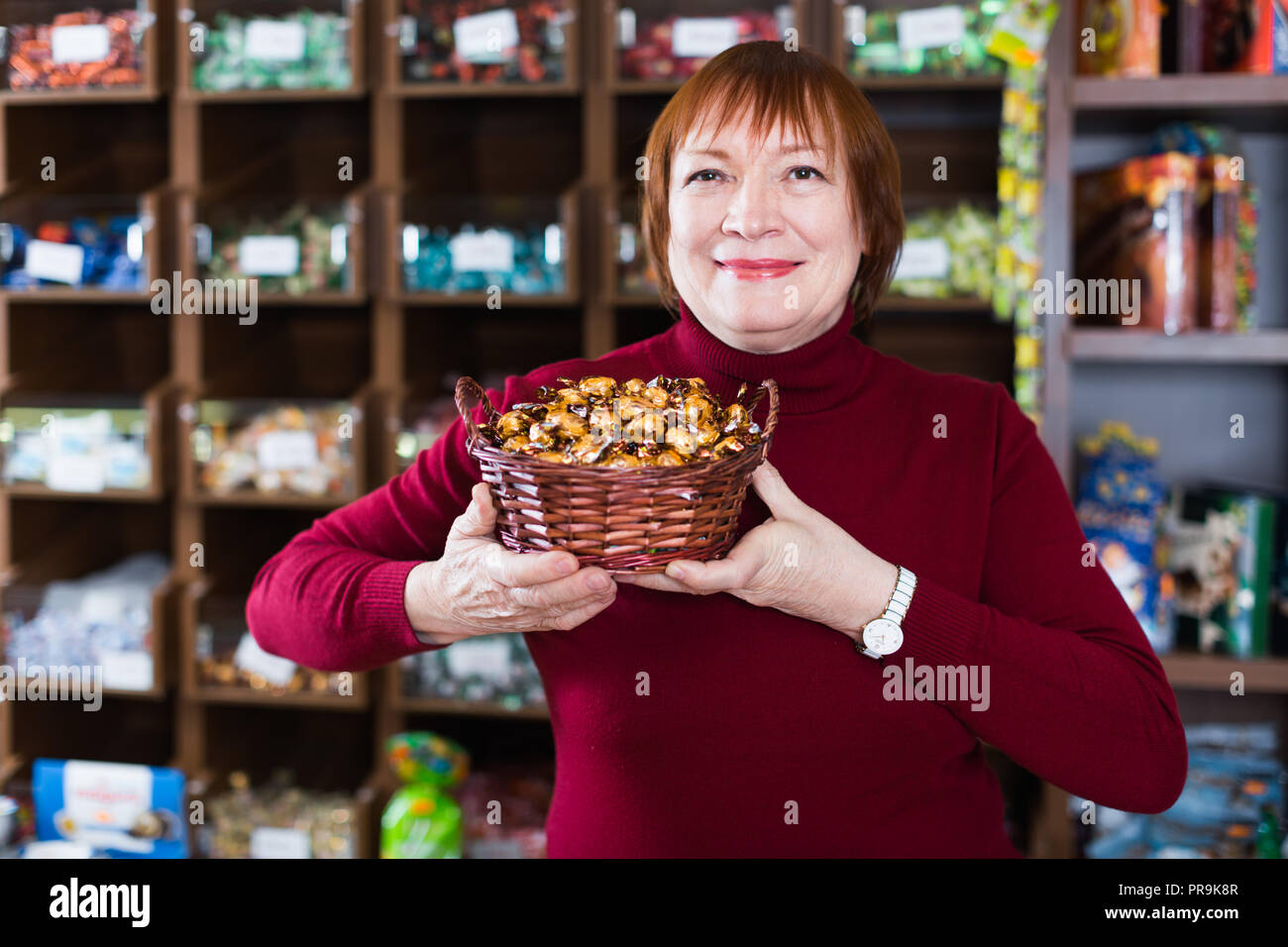 mature female offers sweet candies in the food store Stock Photo - Alamy