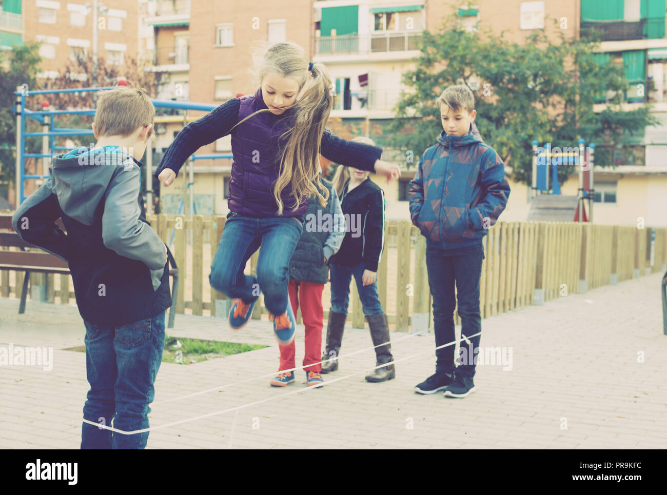 american children playing rubber band jumping game and laughing ...