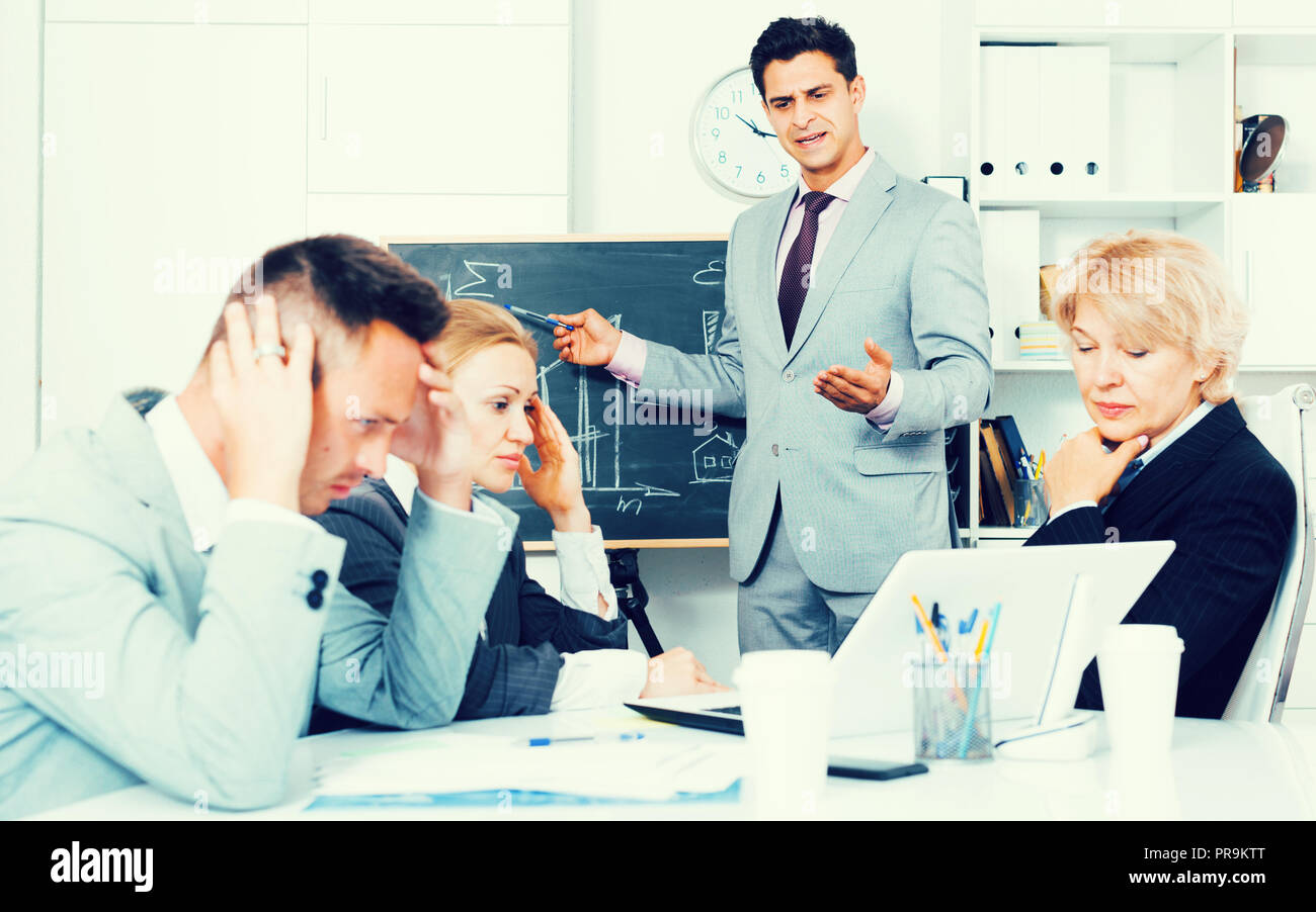 Businessman feeling angry to coworkers in office, pointing at diagrams ...