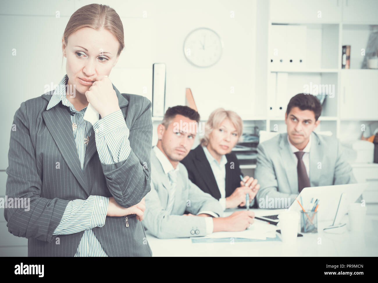 Business woman crying standing in office with working colleagues behind ...
