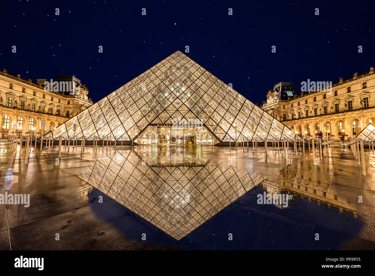 Main entrance to Louvre Museum illuminated at night with starry sky ...