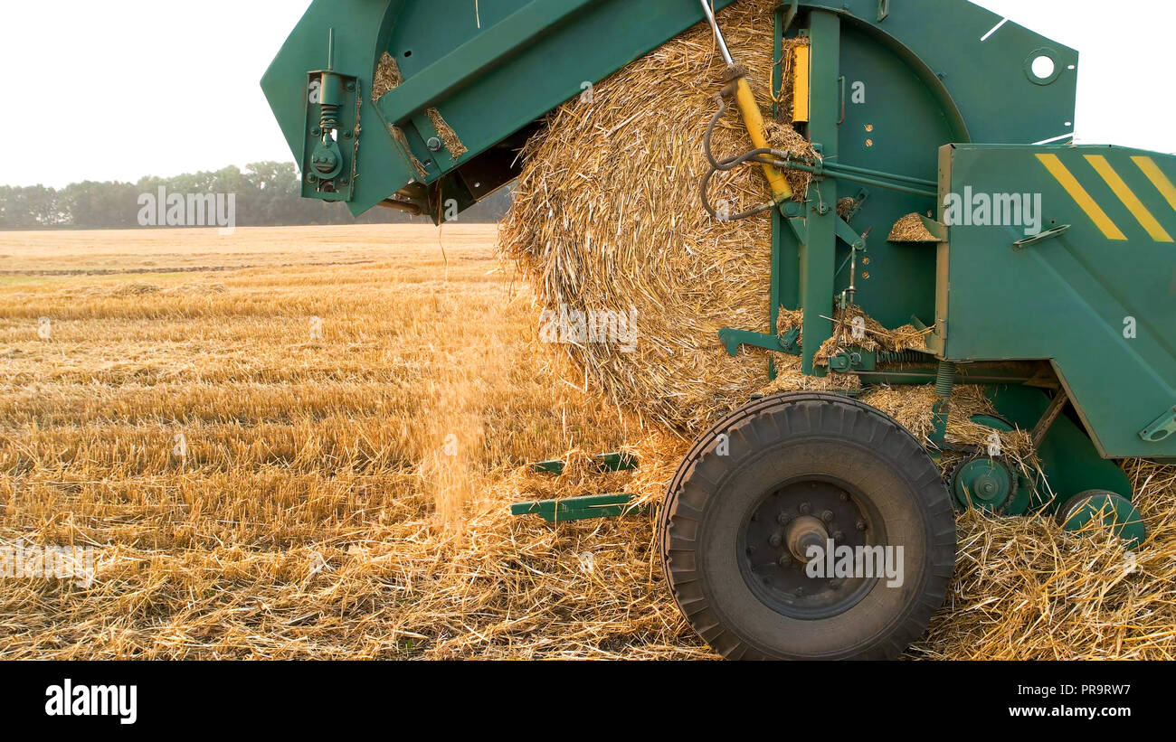 Machine making a round straw bale Stock Photo - Alamy