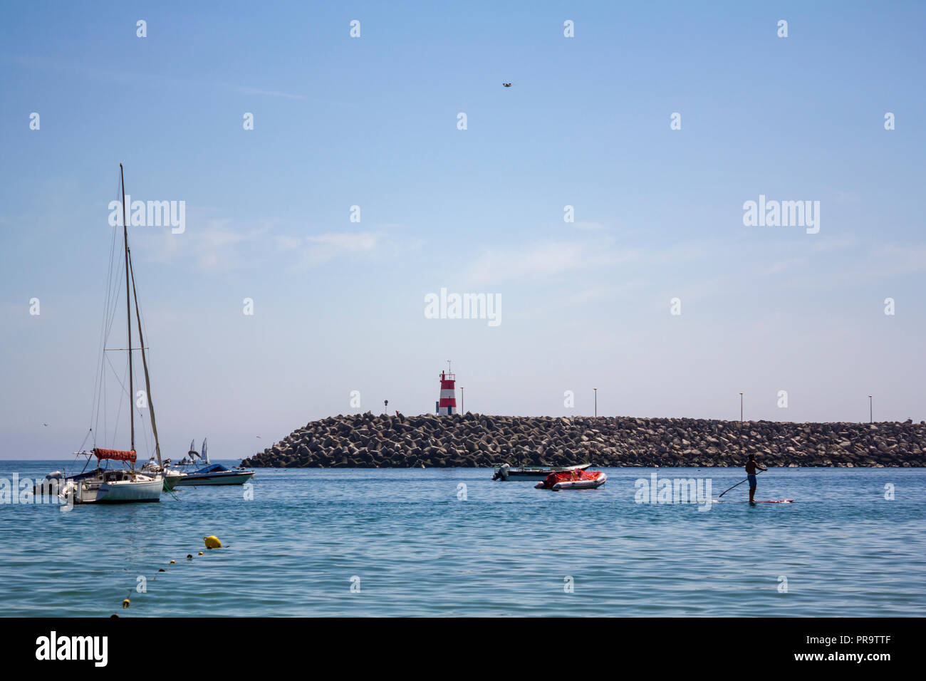 Boats on the sea and pier with red lighthouse Stock Photo - Alamy