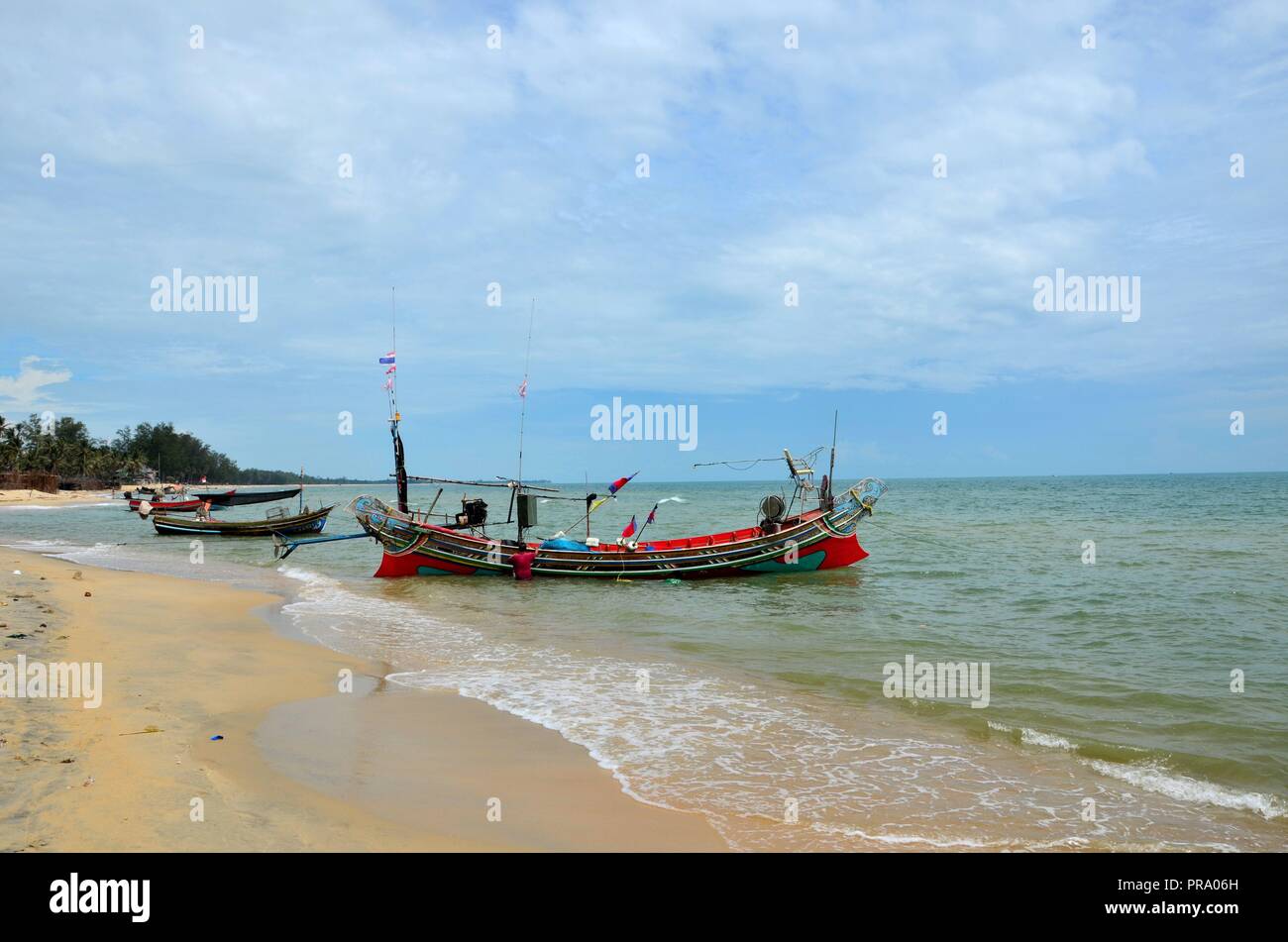 Two Thai fishermen take equipment onto boat at seaside Pattani Thailand ...
