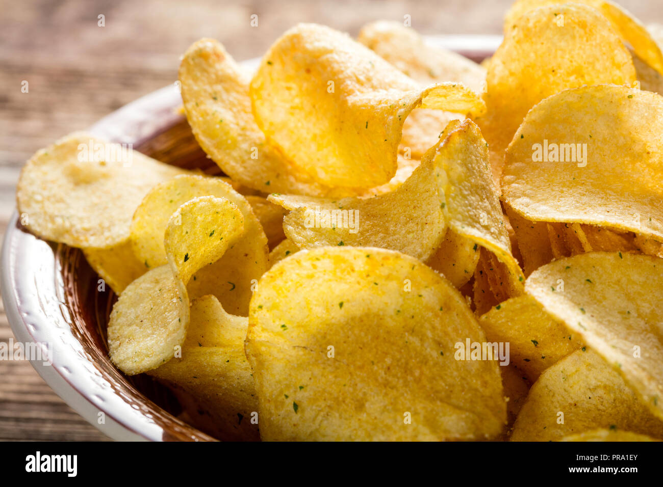 heap of potato chips in bowl on wooden background Stock Photo - Alamy
