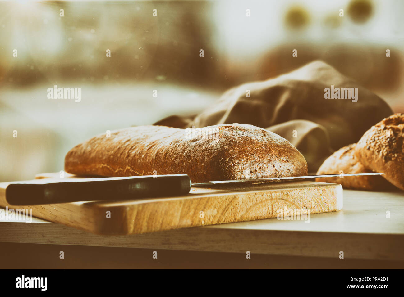 Whole loaf of bread on cutting board on the bench of a kitchen ...