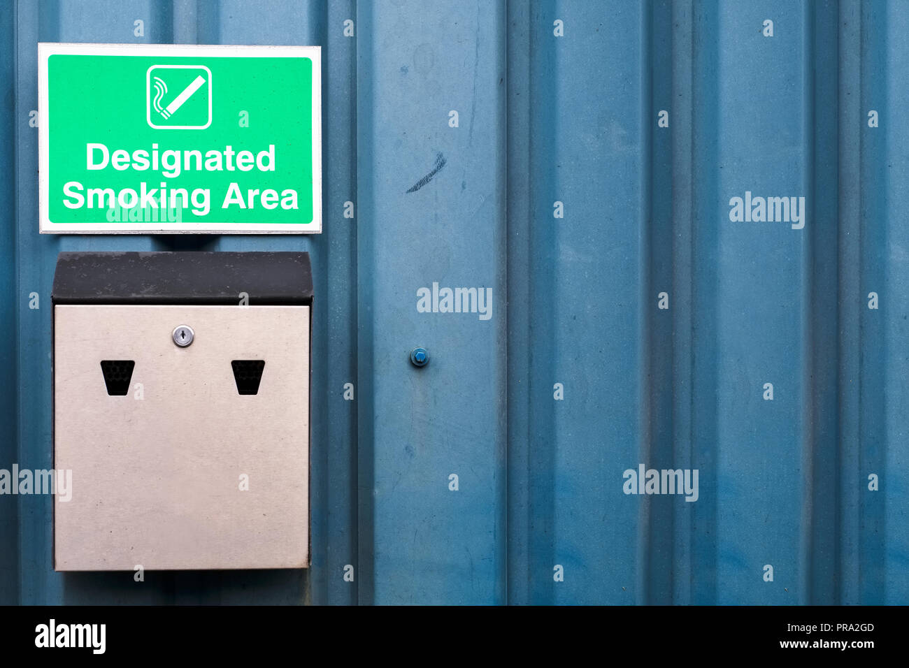 Designated smoking area sign and metal ash tray at work business wall ...