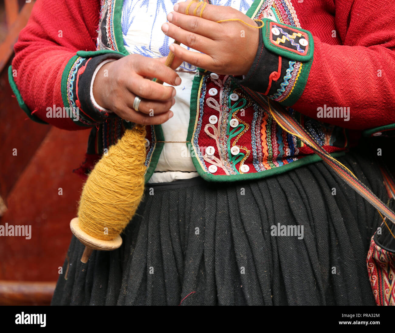 colorful traditional clothes worn by woman holding a spool of yellow ...