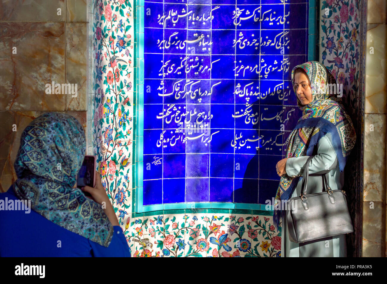 A woman posing for a photo next to a verse of one of Saadi's poems by ...