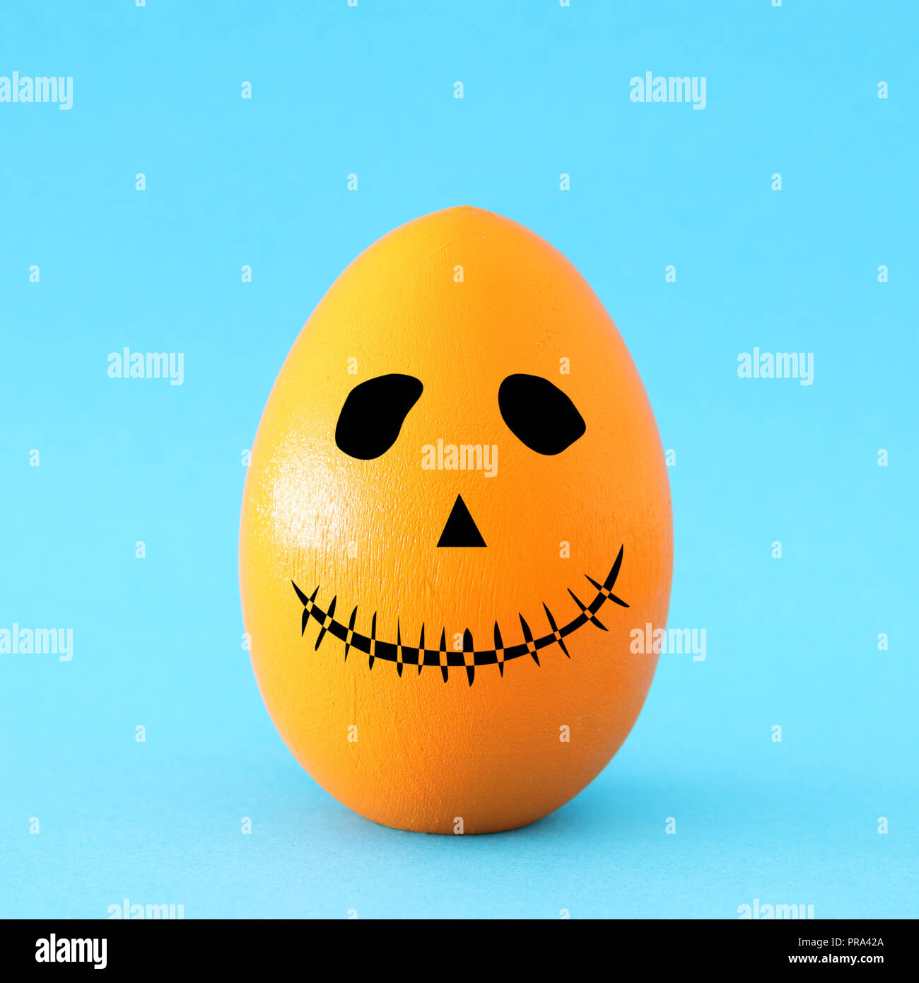 minimal and funny Halloween holiday concept. Orange egg with scary cute ...