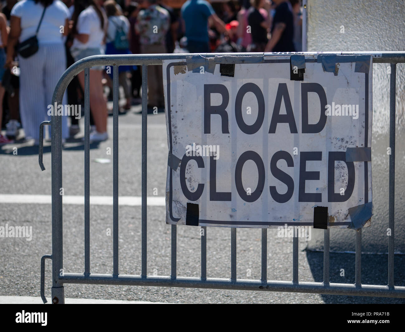 Make shift road closed sign hanging on barrier with crowd in back Stock ...