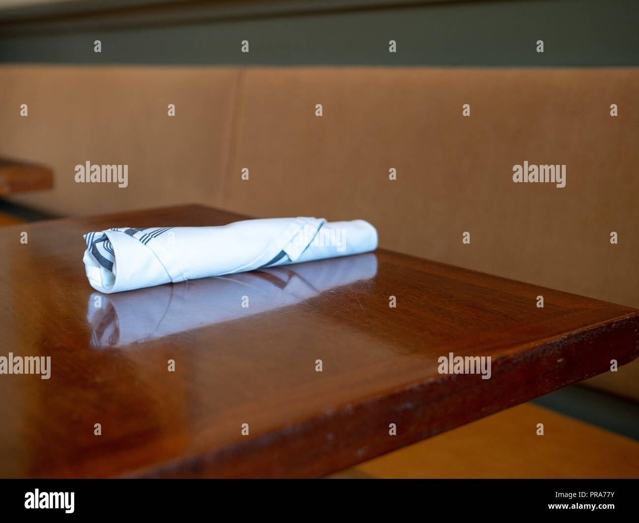 Napkin with utensils inside sitting on restaurant table, prepared for ...