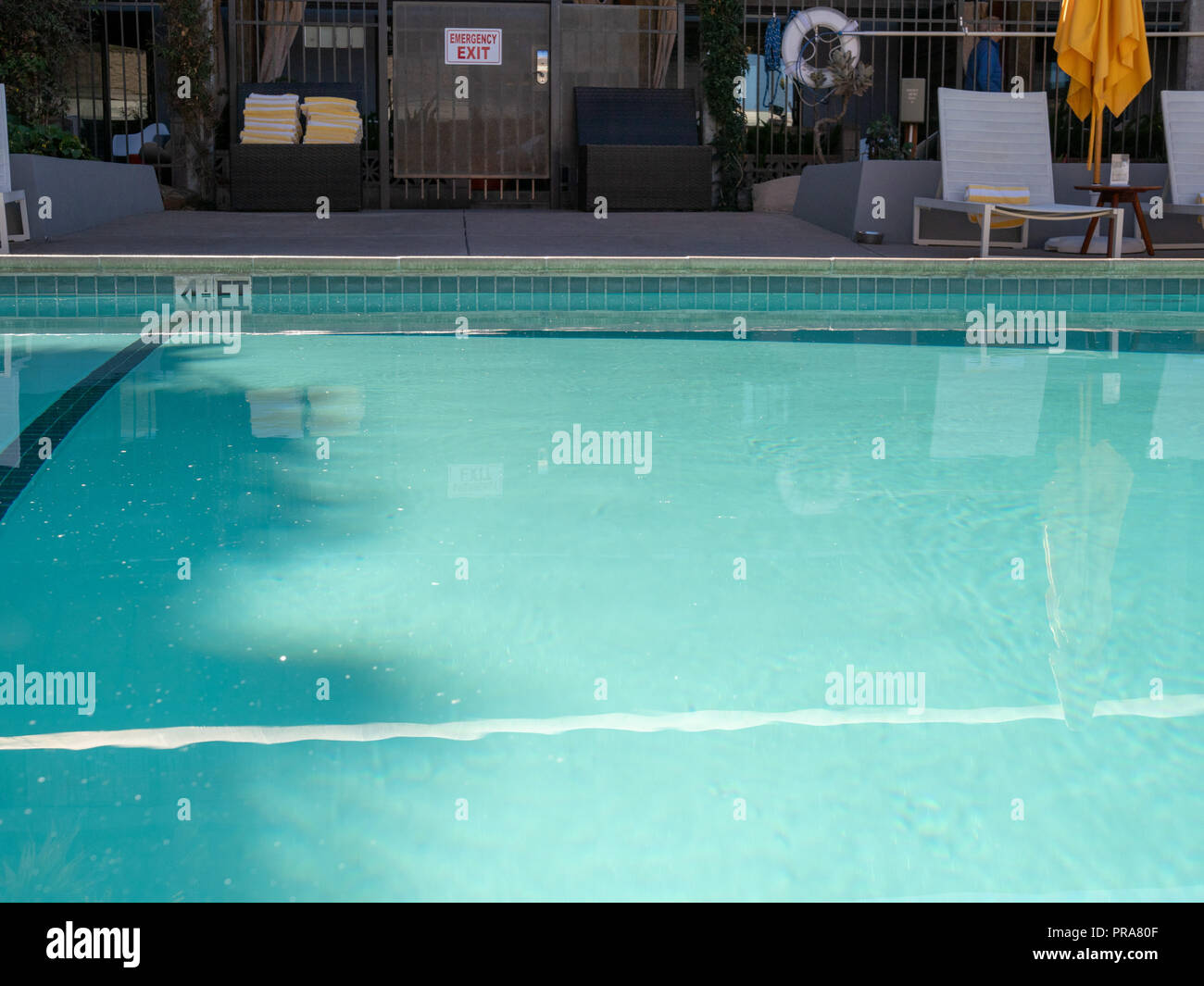 Resort pool with emergency exit, towels, lounge chairs, and equipment ...