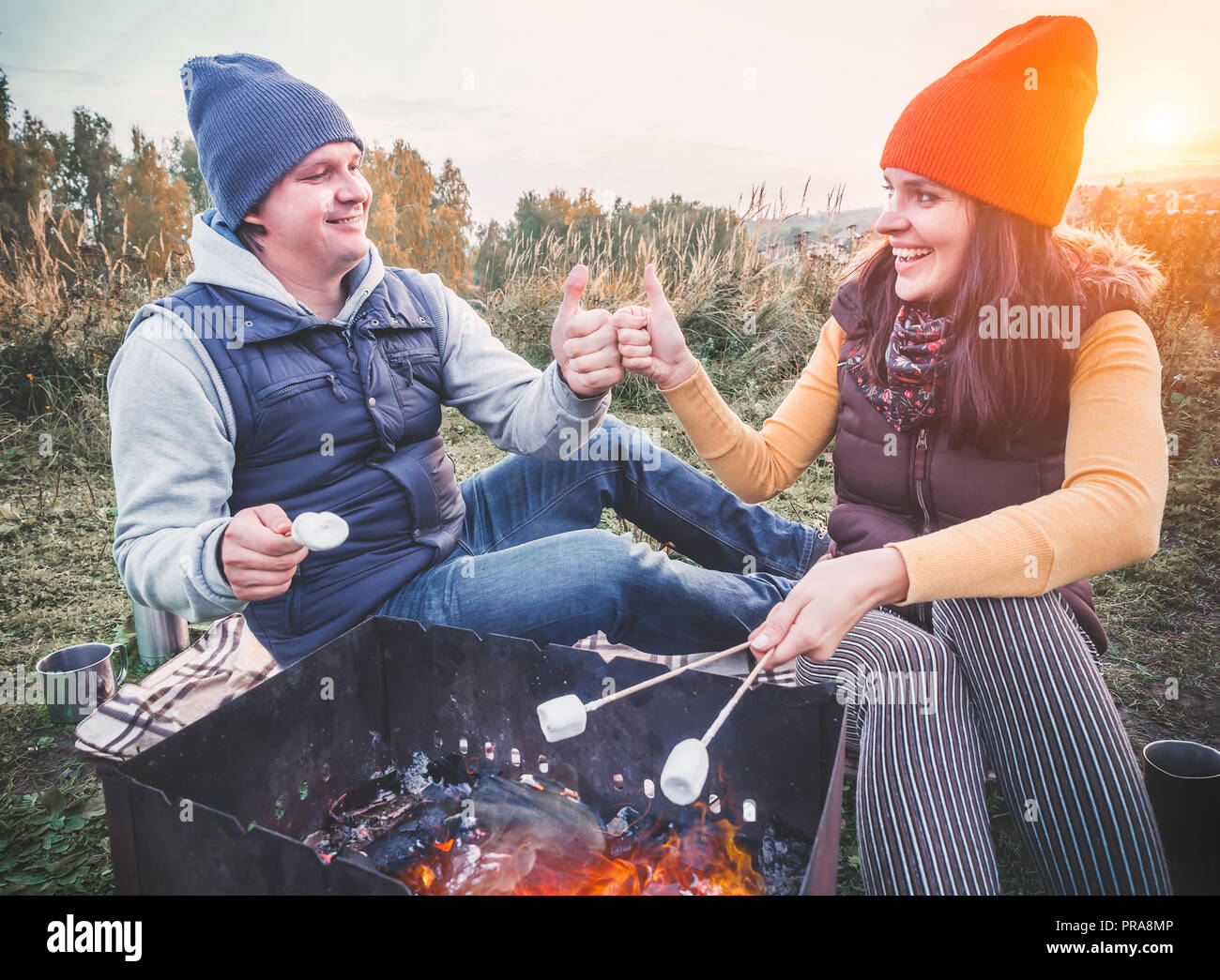 Happy Smiling Couple Roasting Marshmallows On Campfire And Keep Their