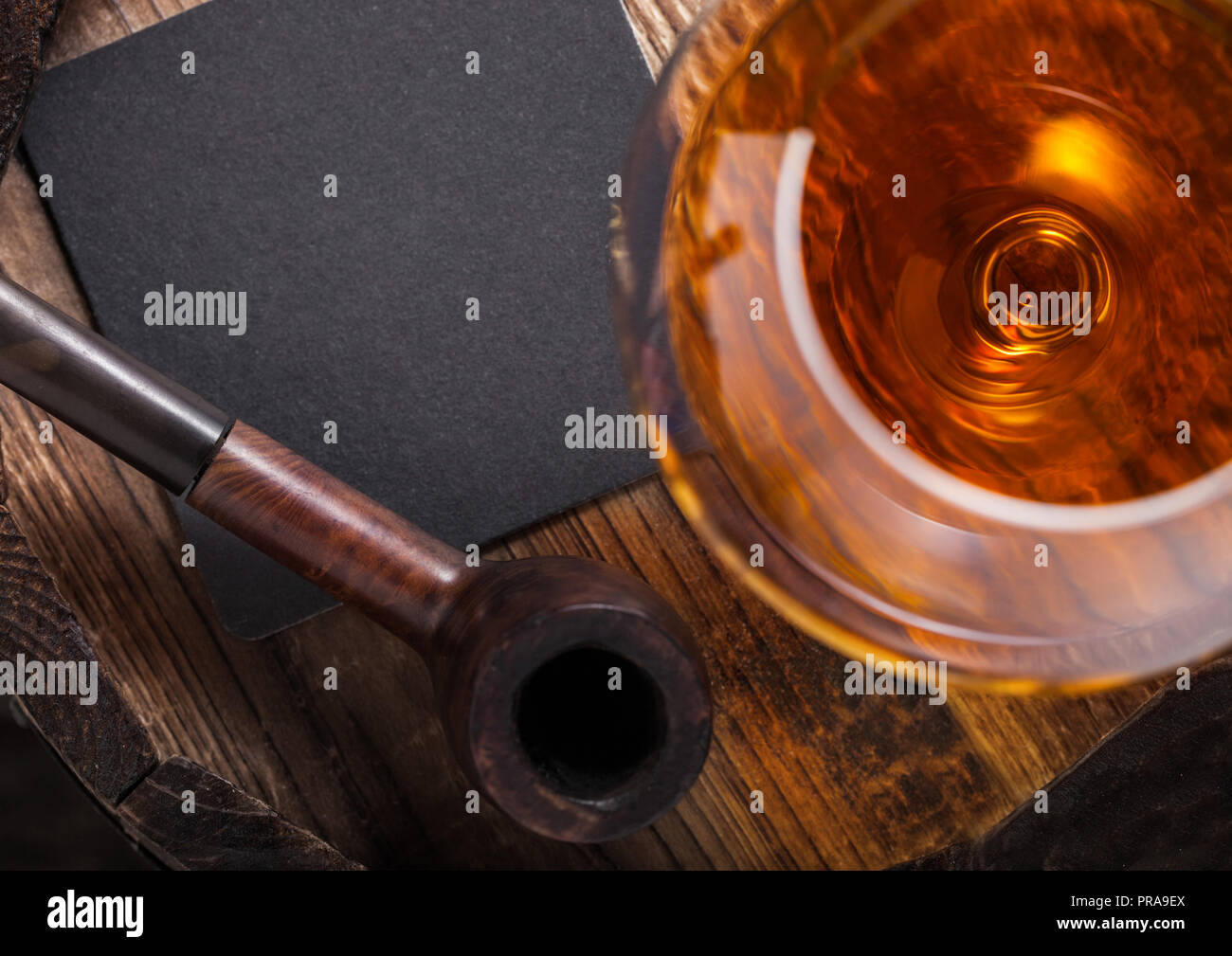 Glass of cognac brandy drink and vintage smoking pipe on top of wooden ...
