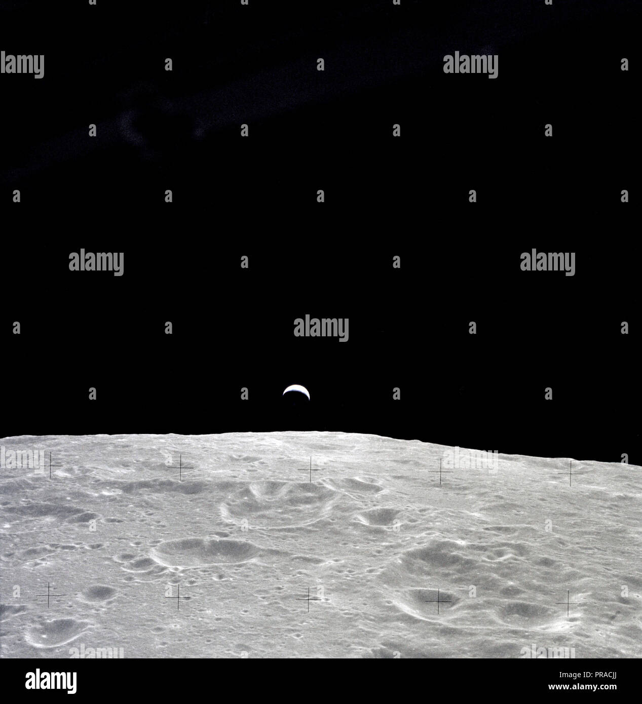 A partially illuminated Earth rises above the lunar horizon in this ...