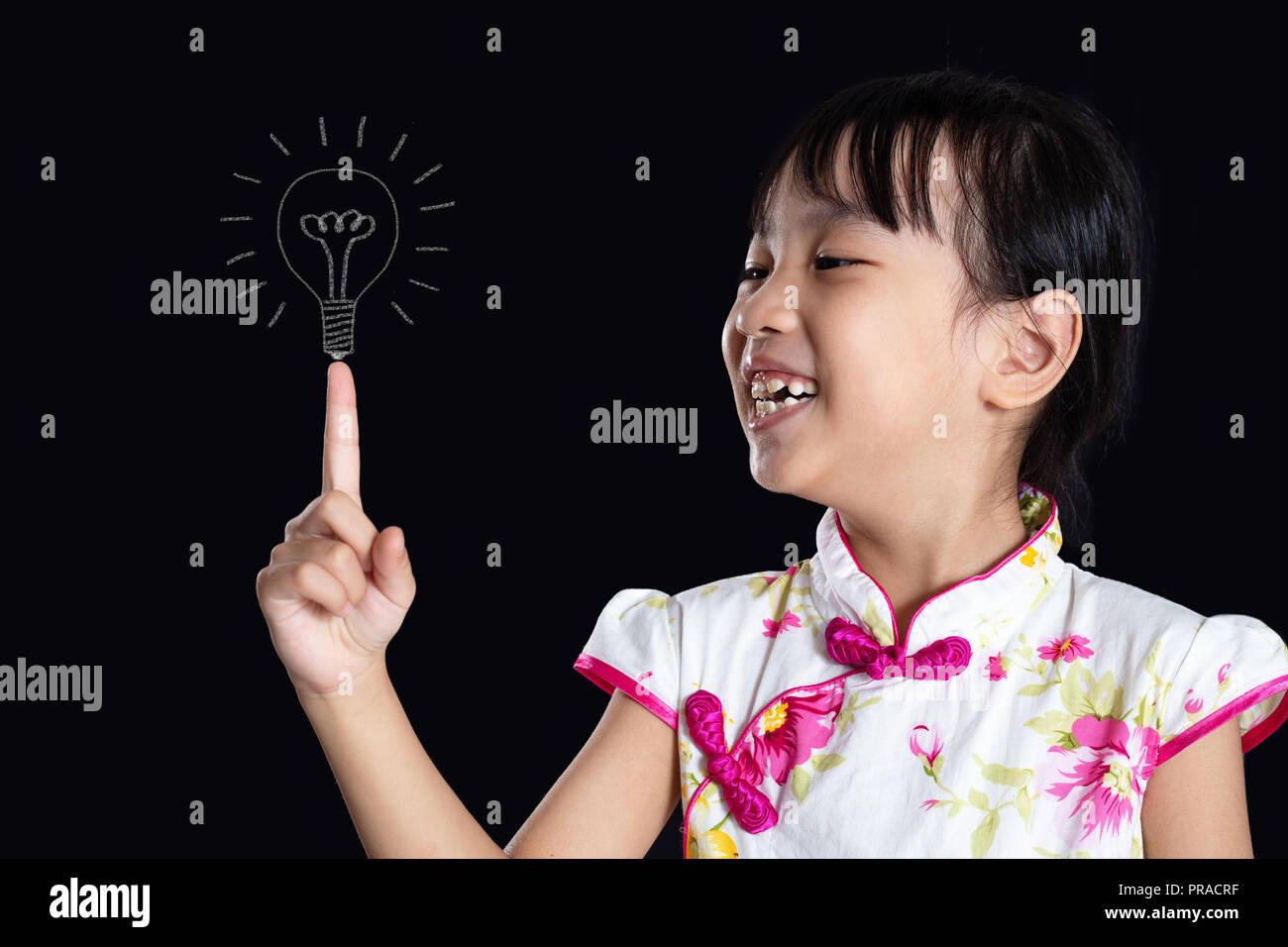 Asian chinese little girl pointing finger up to bulb in isolated black ...