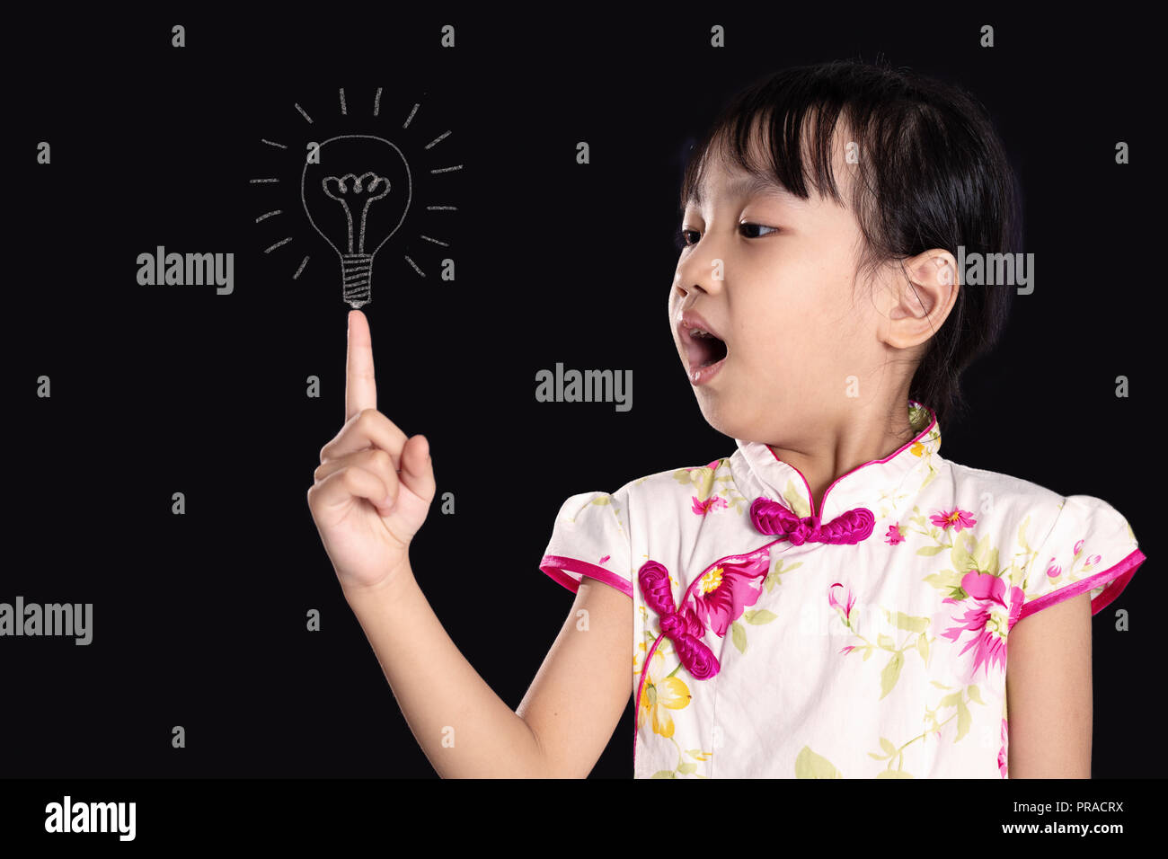 Asian chinese little girl pointing finger up to bulb in isolated black ...