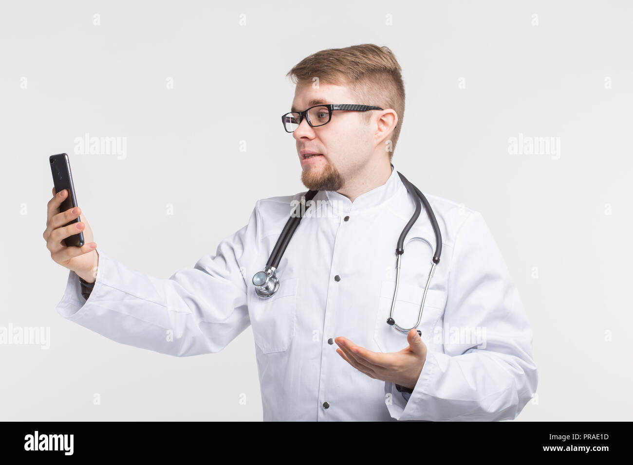 Happy male doctor making selfie photo with smartphone on white ...