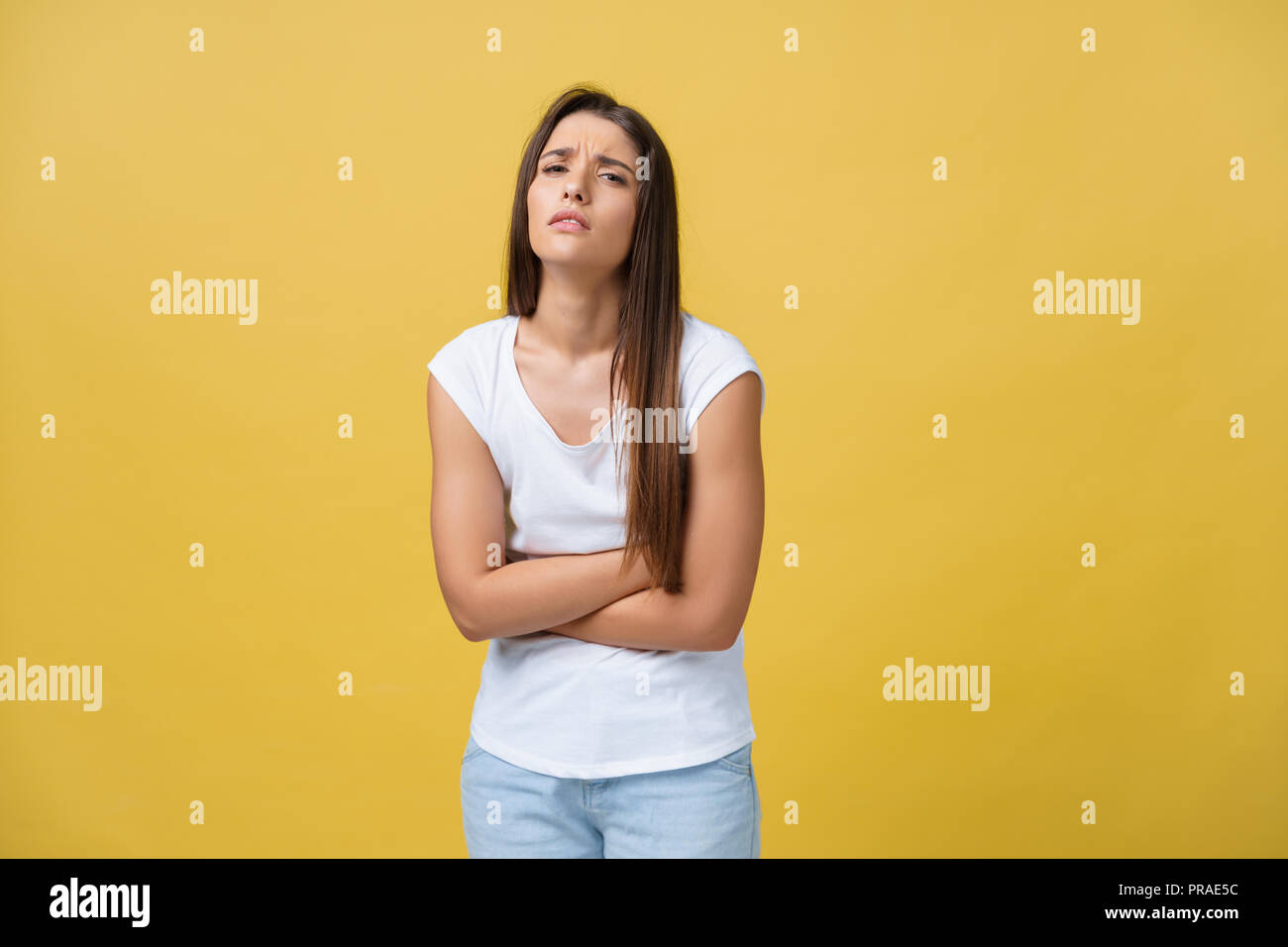 Indoor portrait of cute girl standing with crossed hands on belly ...