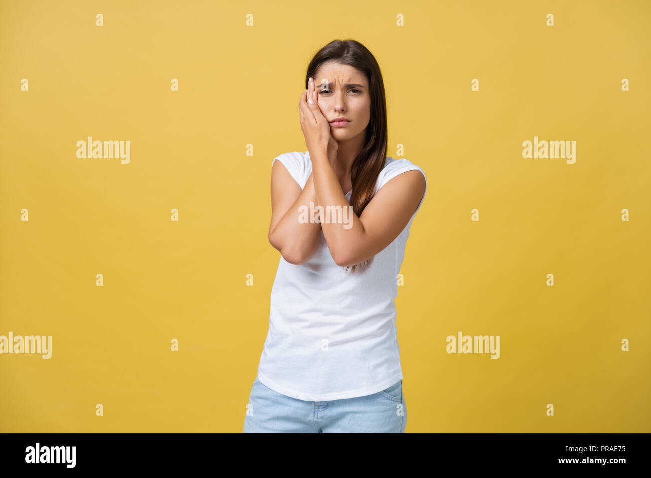 young woman has a toothache, studio photo isolated on a yellow ...